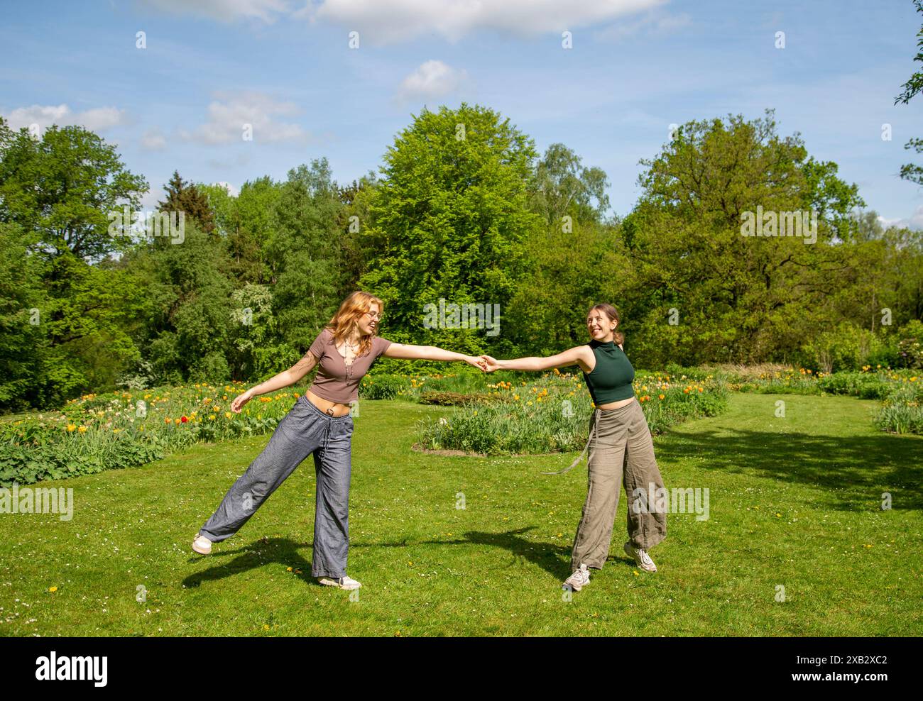 Two friends enjoy a playful moment in a lush green park, embracing ...