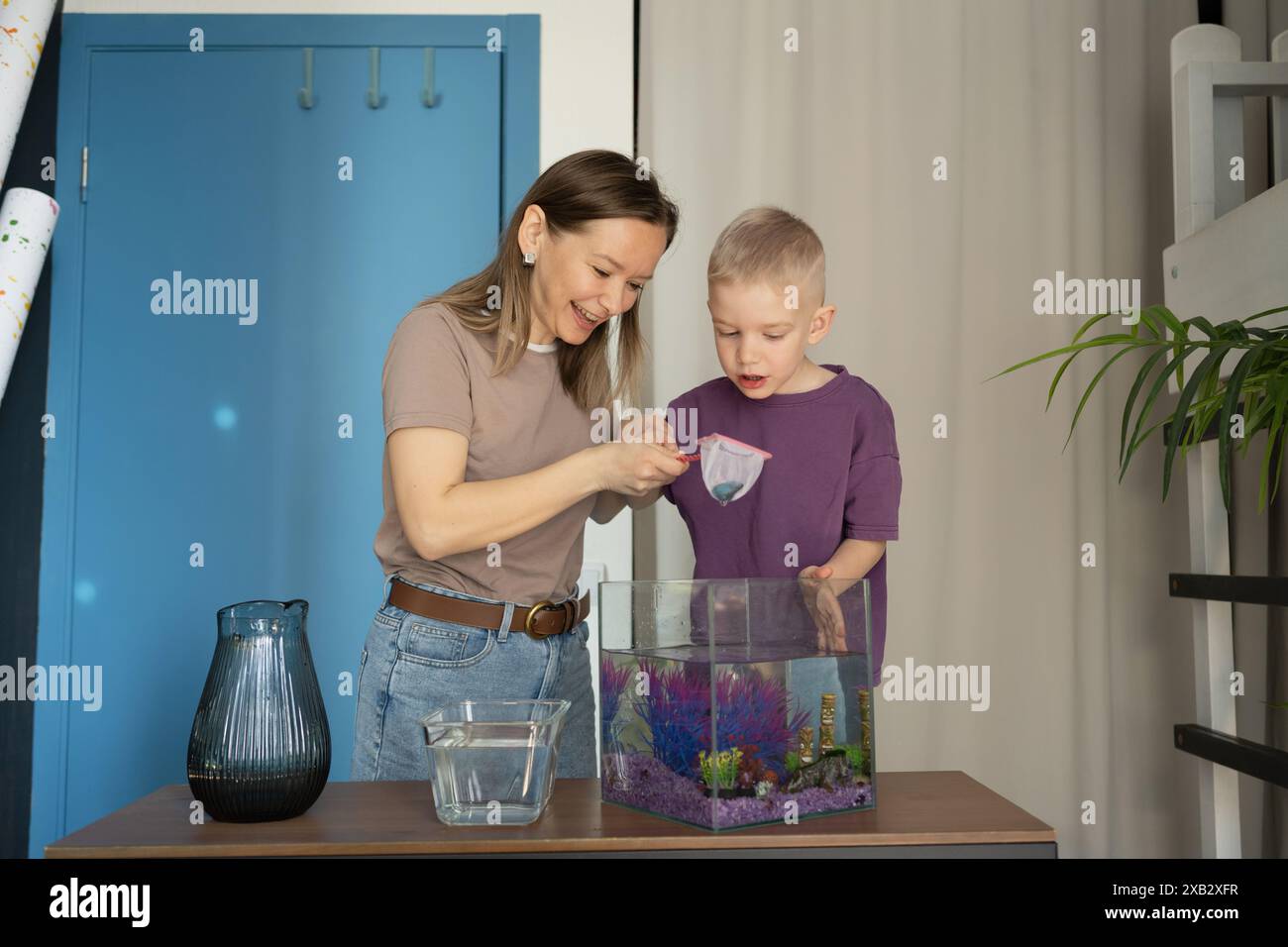 A smiling woman and her young son are gently placing a fish into a home ...