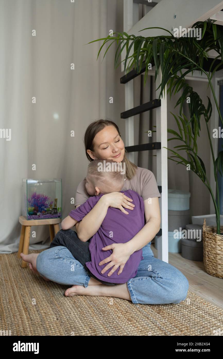 A woman embracing her child near an aquarium at home, both looking content Stock Photo - Alamy