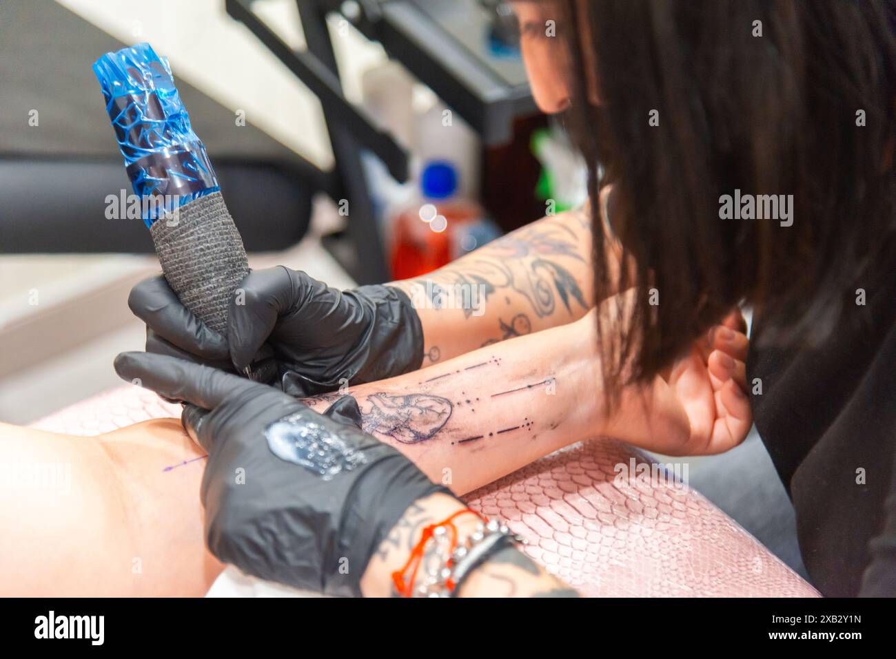 An anonymous tattoo artist applies ink to a faceless client's arm ...
