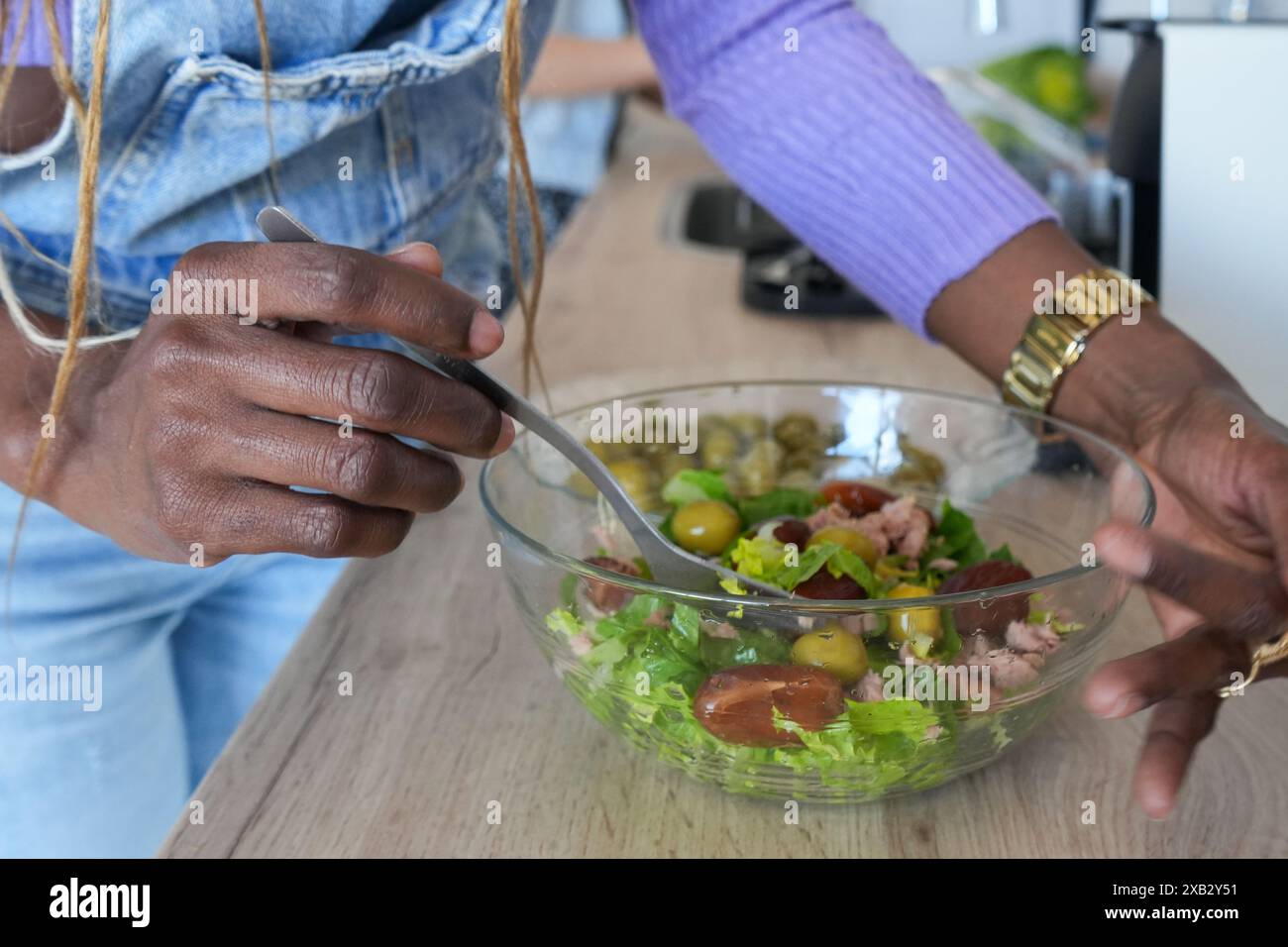 Close-up view of a person tossing a mixed green salad with various ...