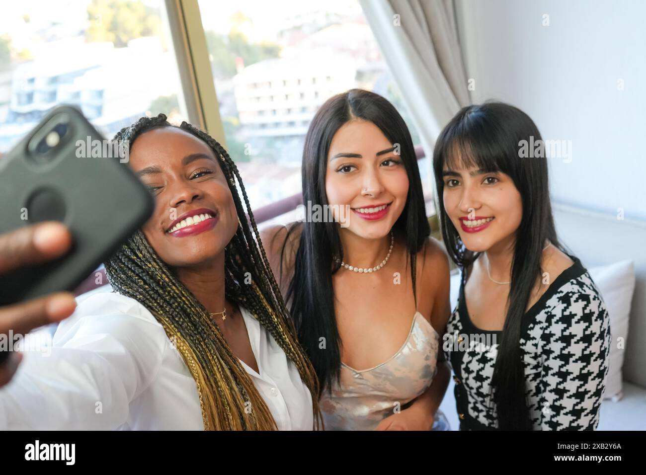 Three young women of diverse backgrounds share a joyful moment while ...