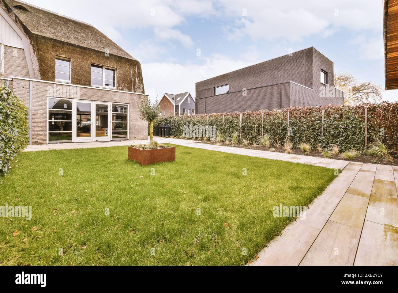 Neat paved patio with sitting area and small garden near wooden fence ...