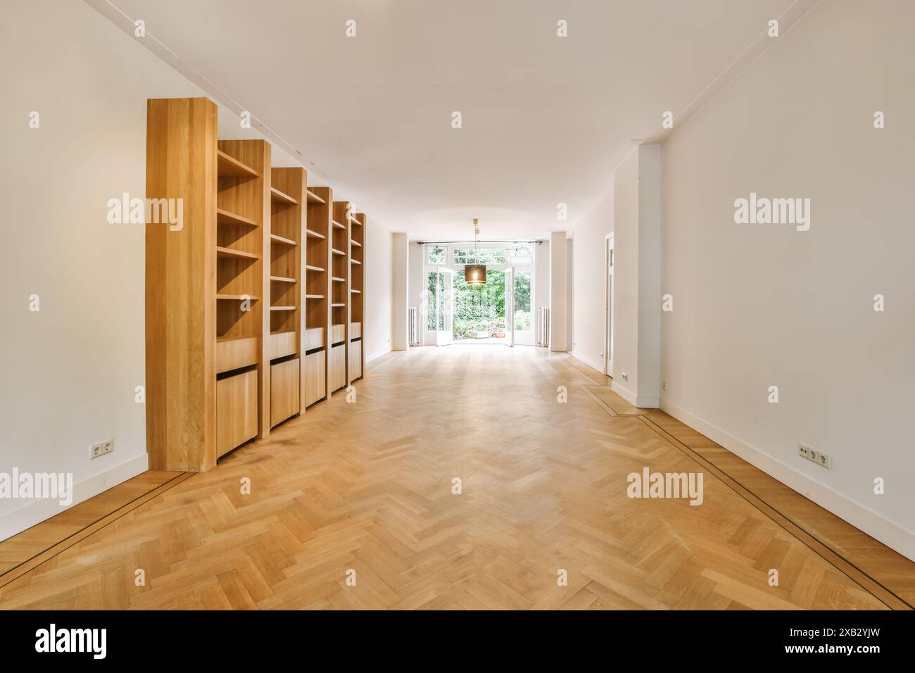 A bright, spacious living room featuring herringbone hardwood floors, a ...