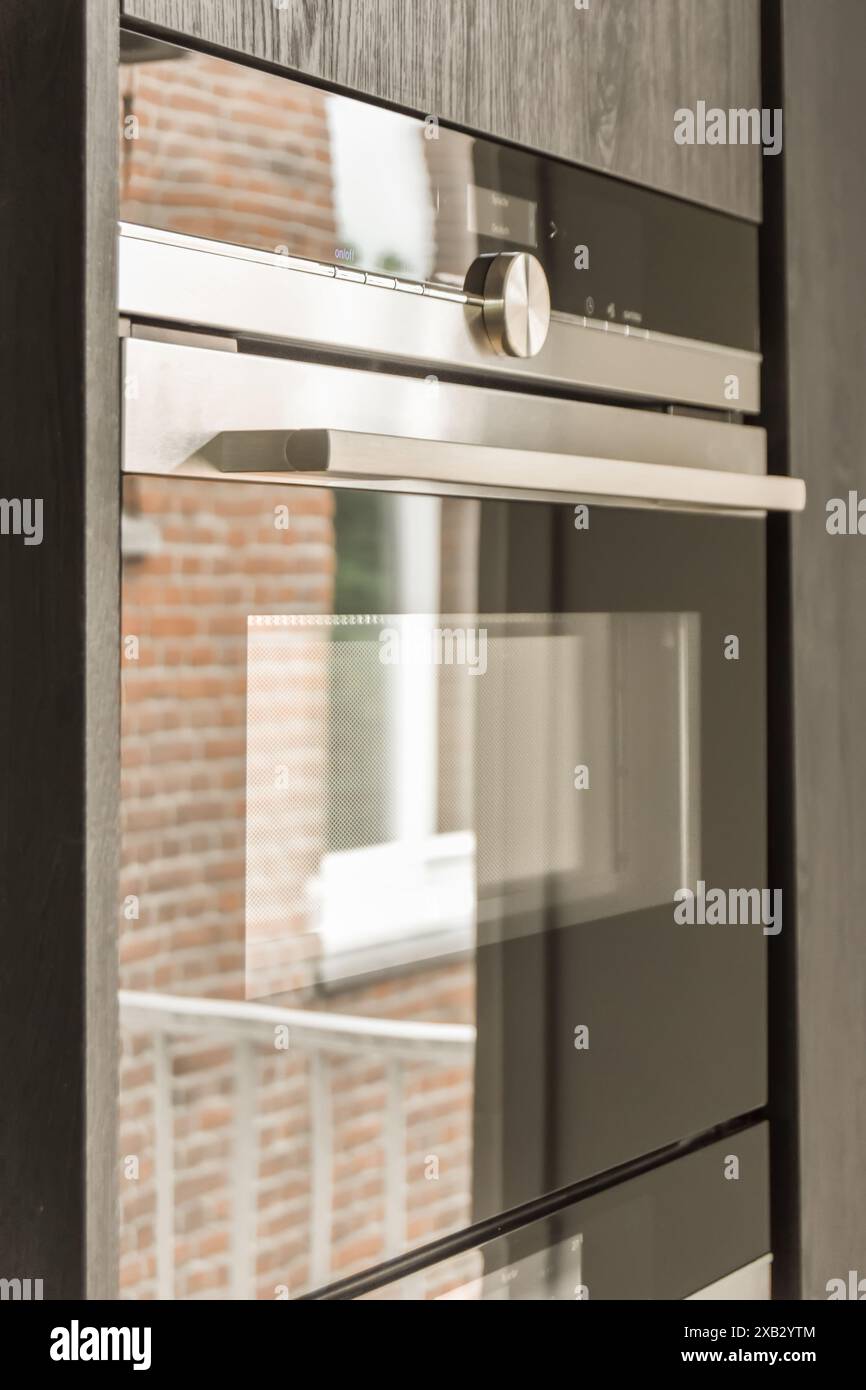 Close-up of a contemporary stainless steel oven built into dark wood ...