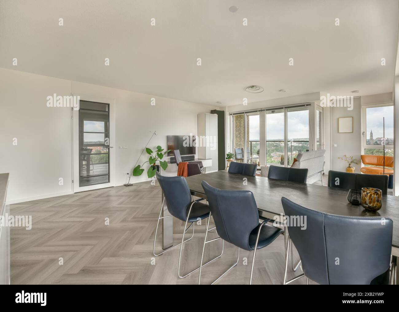Airy dining space with herringbone wood flooring, a large table, chic ...
