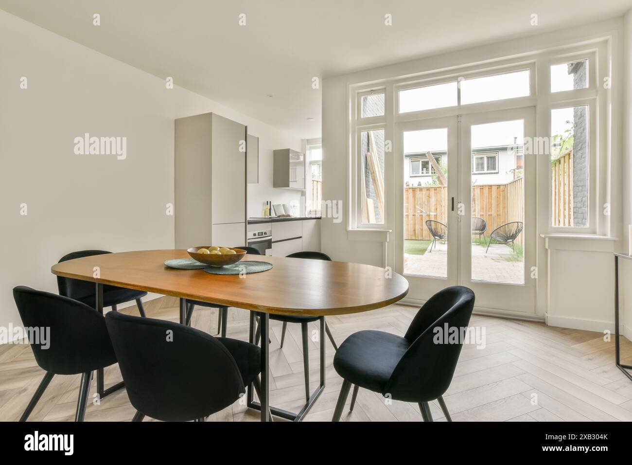 Contemporary dining room featuring a wooden table, black chairs, and ...