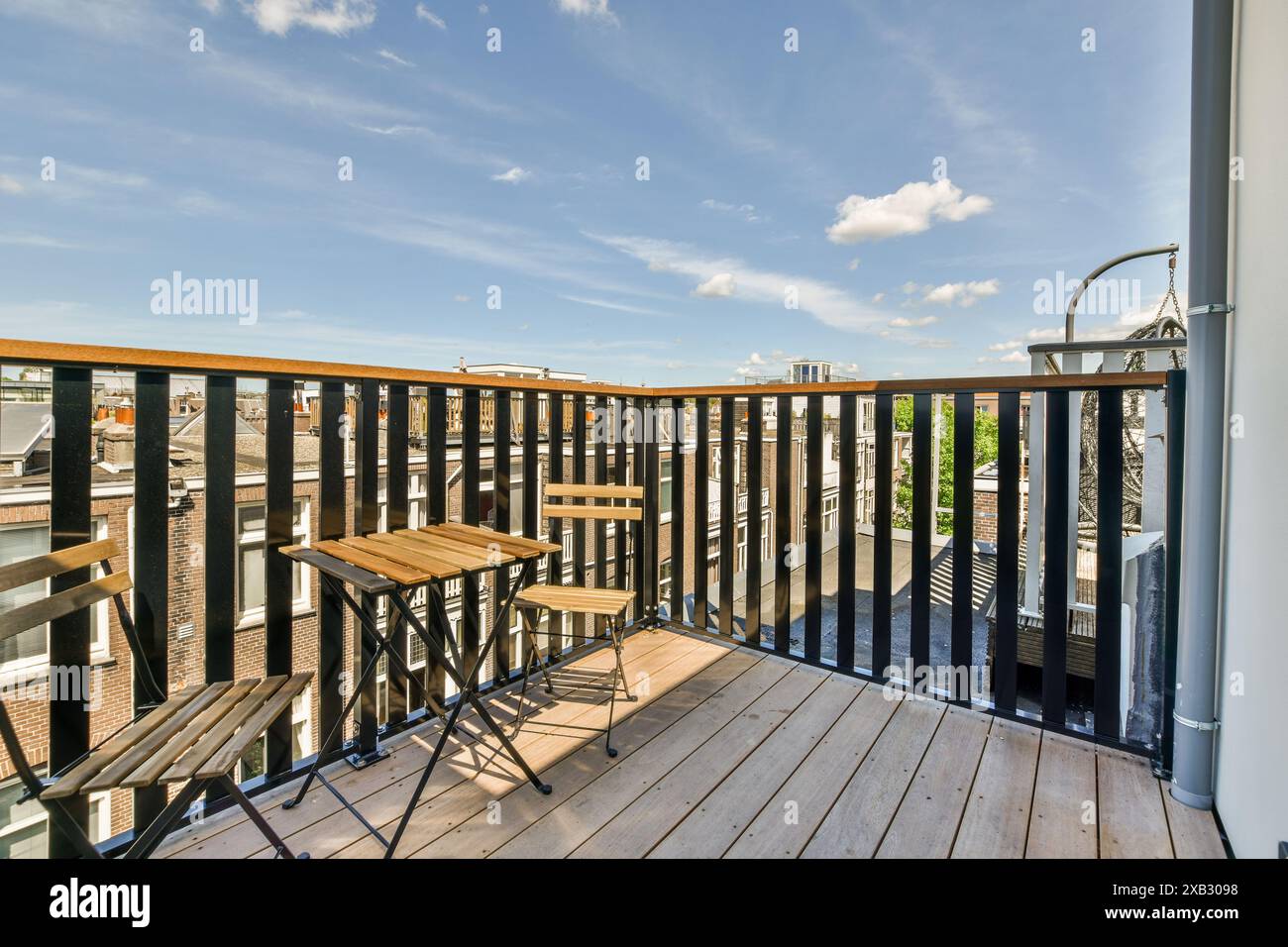 A charming urban balcony showcasing a modest wooden table and chairs ...