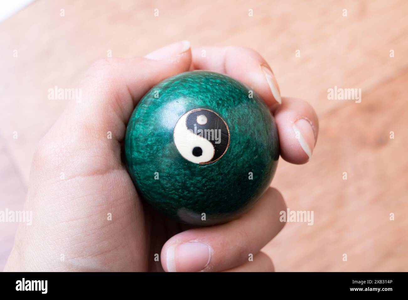 In the image, a person is grasping a green ball adorned with a yin yang ...