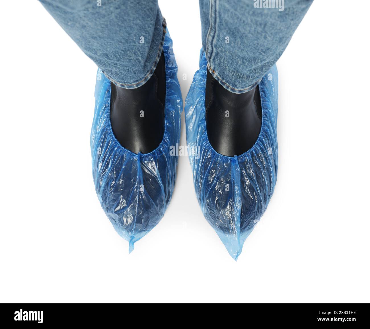 Woman wearing blue shoe covers onto her boots against white background ...