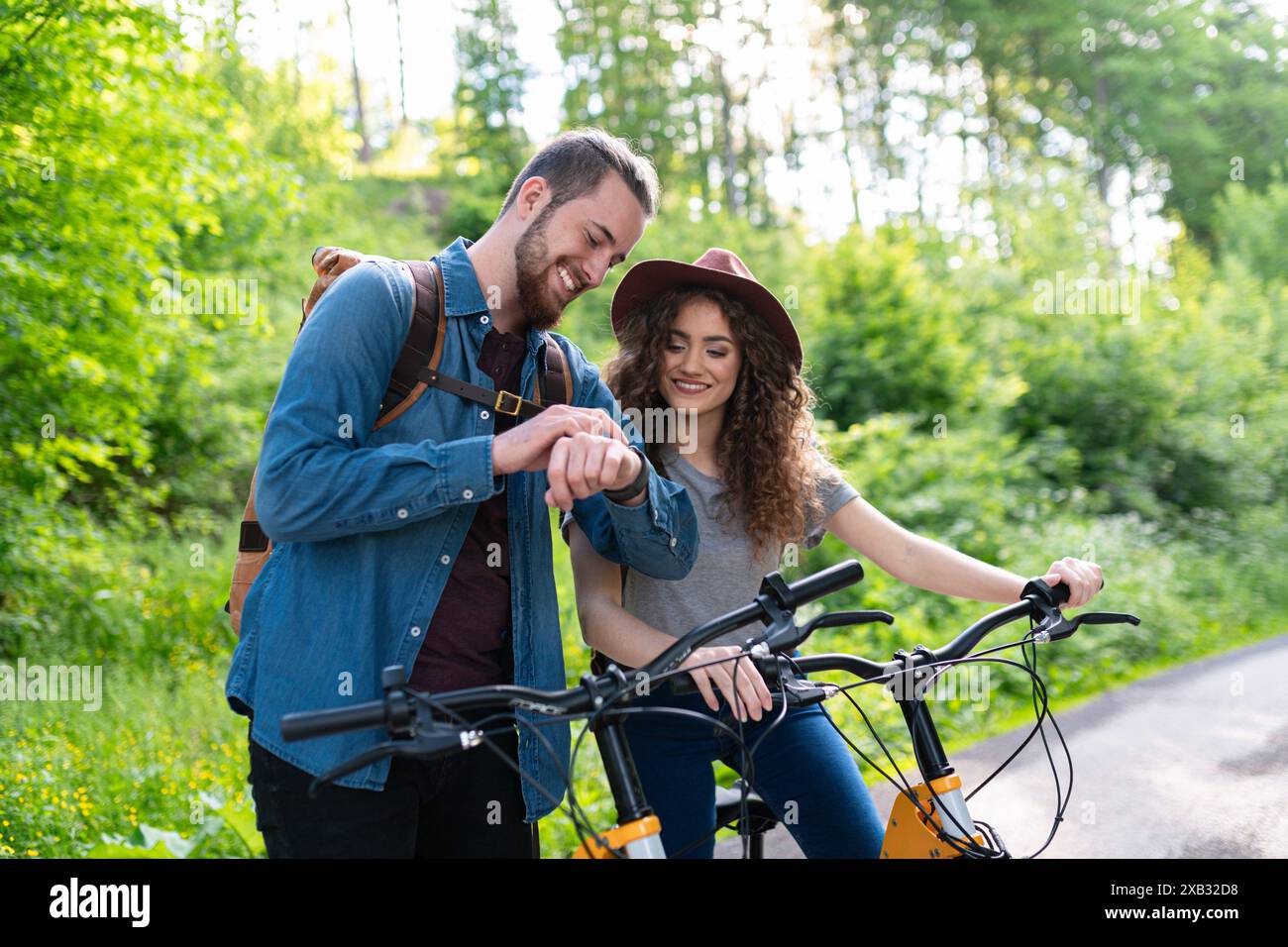 Travellers couple going on e-bike ride in nature. Tourist riding electric bicycles on easy trail ...