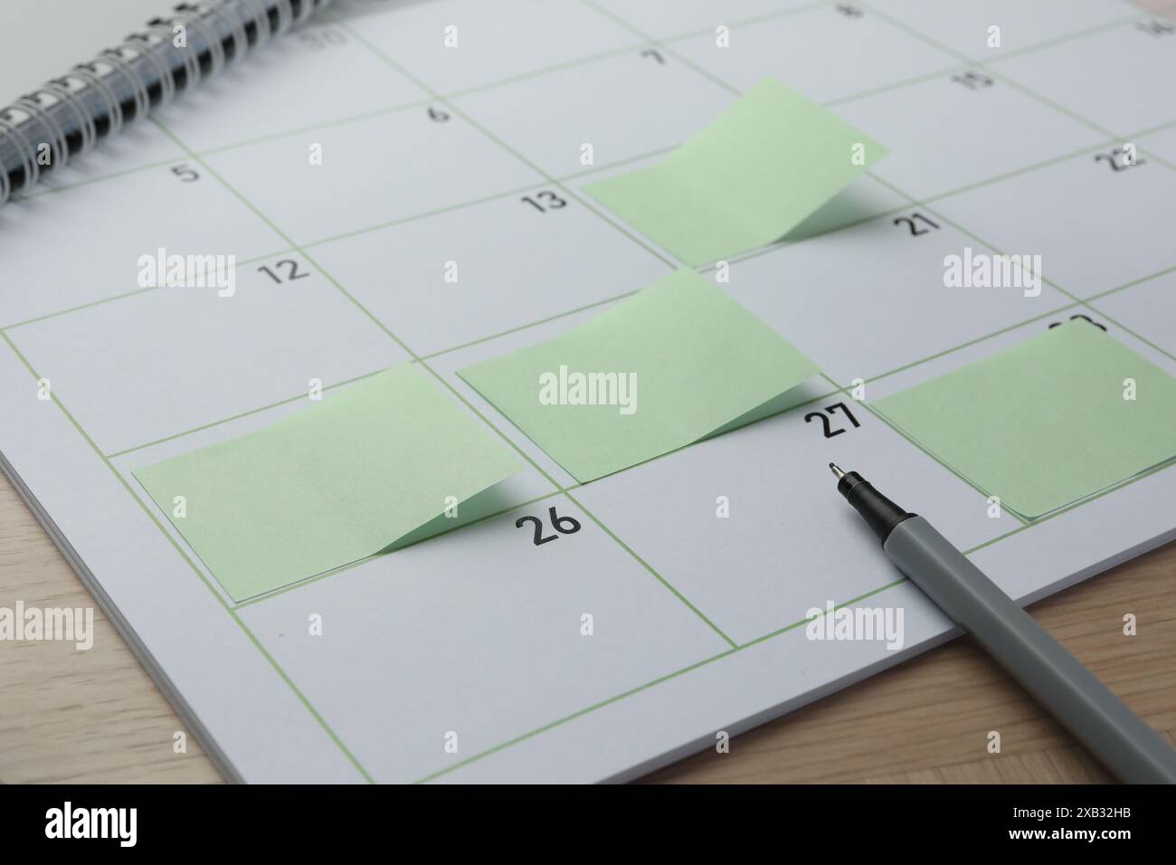 Timetable. Calendar page with green sticky notes and pen on wooden ...