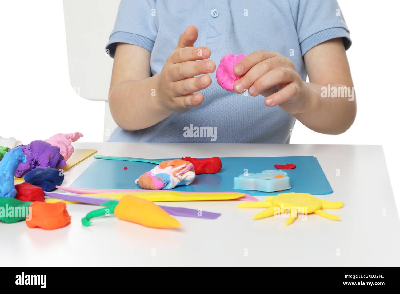 Little boy sculpting with play dough at table on white background ...