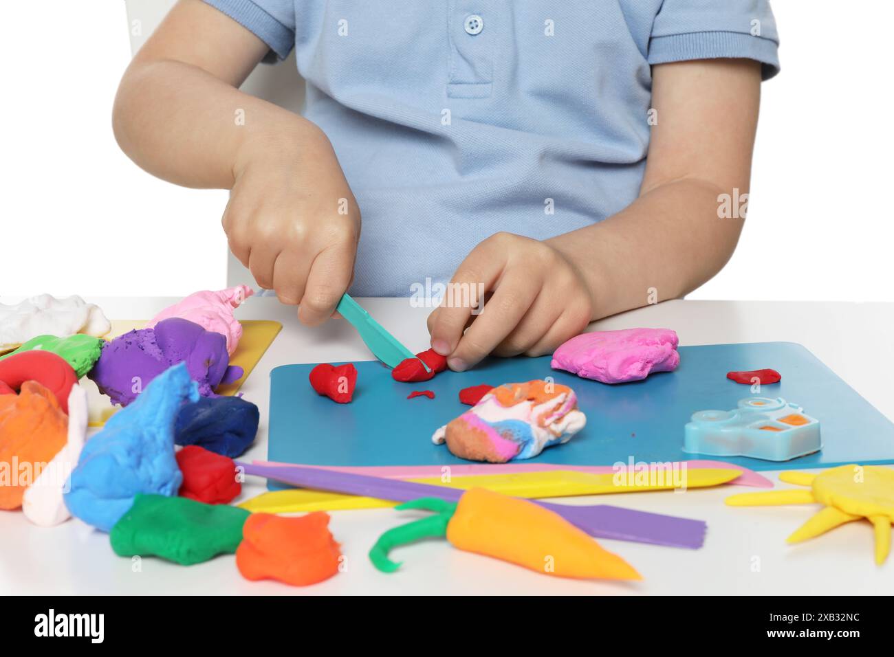Little boy sculpting with play dough at table on white background ...