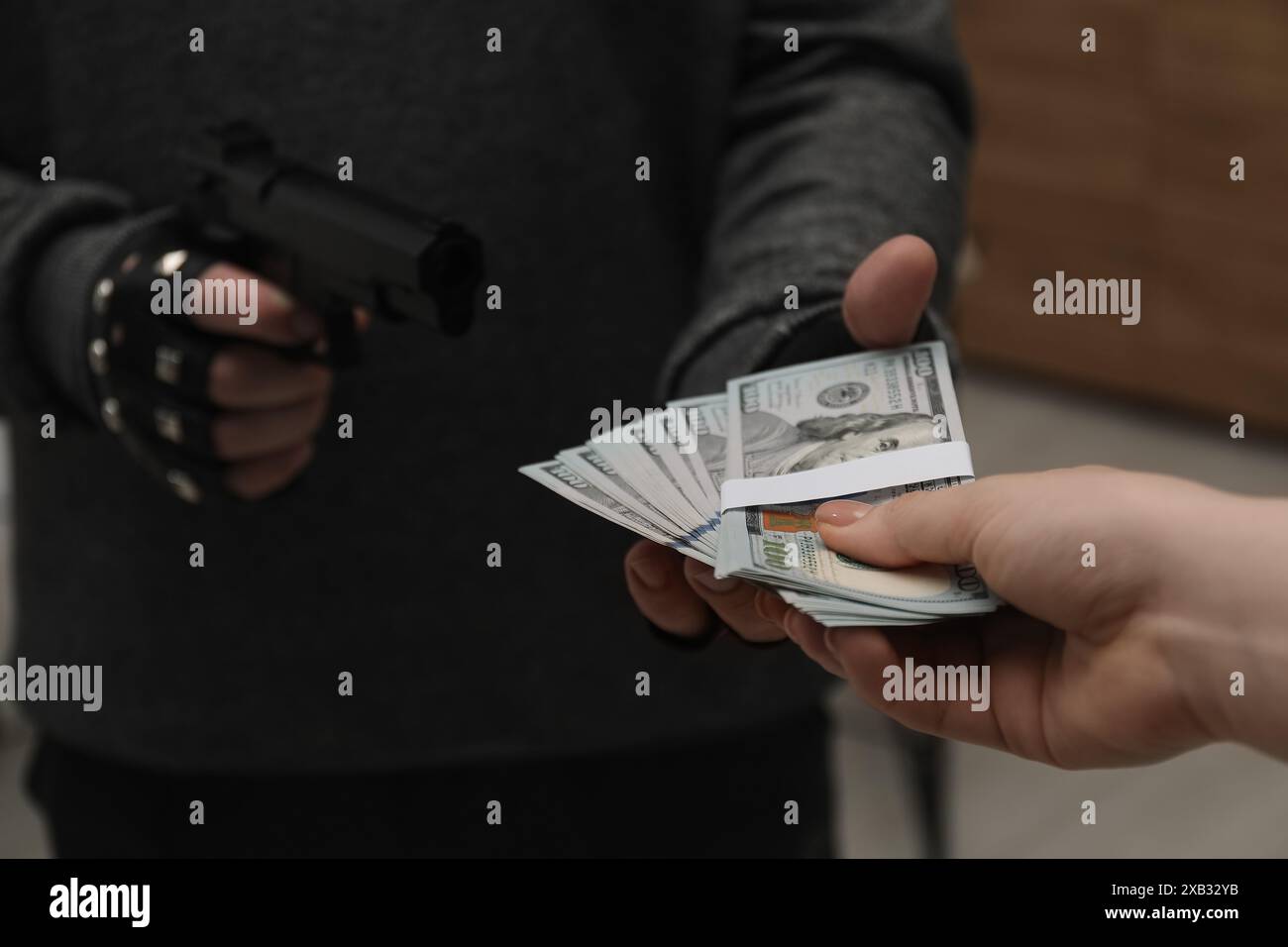 Woman giving money to criminal with gun indoors, closeup. Armed robbery ...