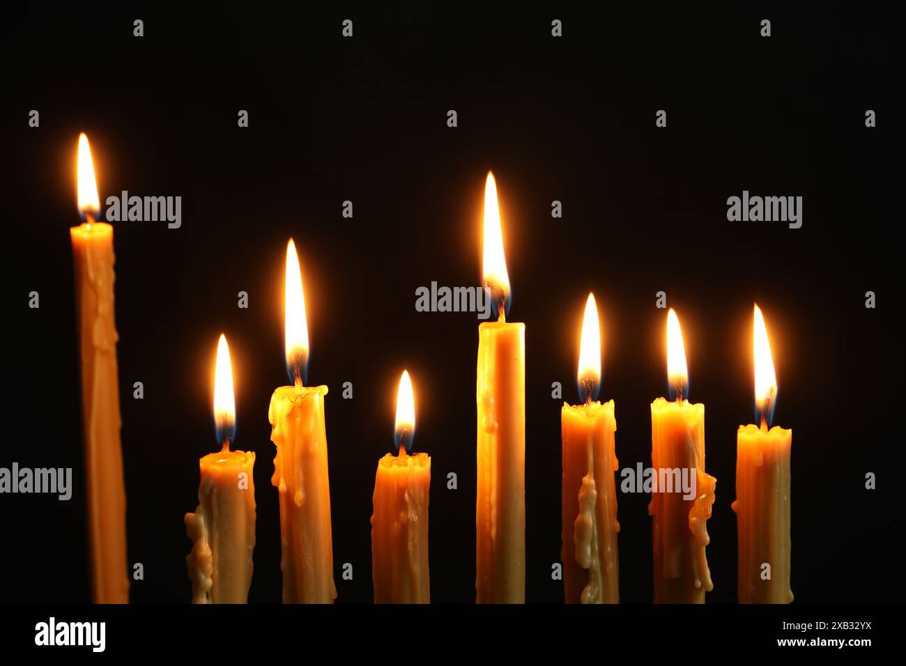 Many burning church candles on black background Stock Photo - Alamy