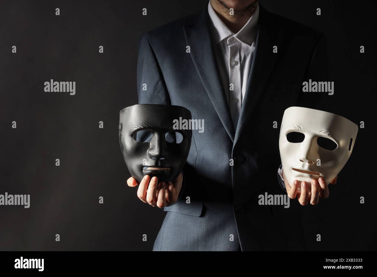 Theatrical performance. Man holding plastic masks on black background ...