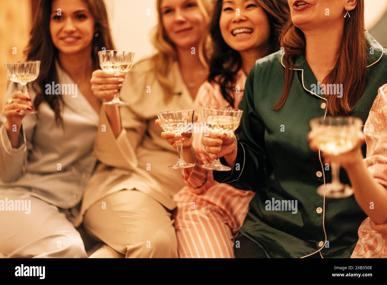 Happy girls with glasses of champagne laugh and raise a festive toast ...