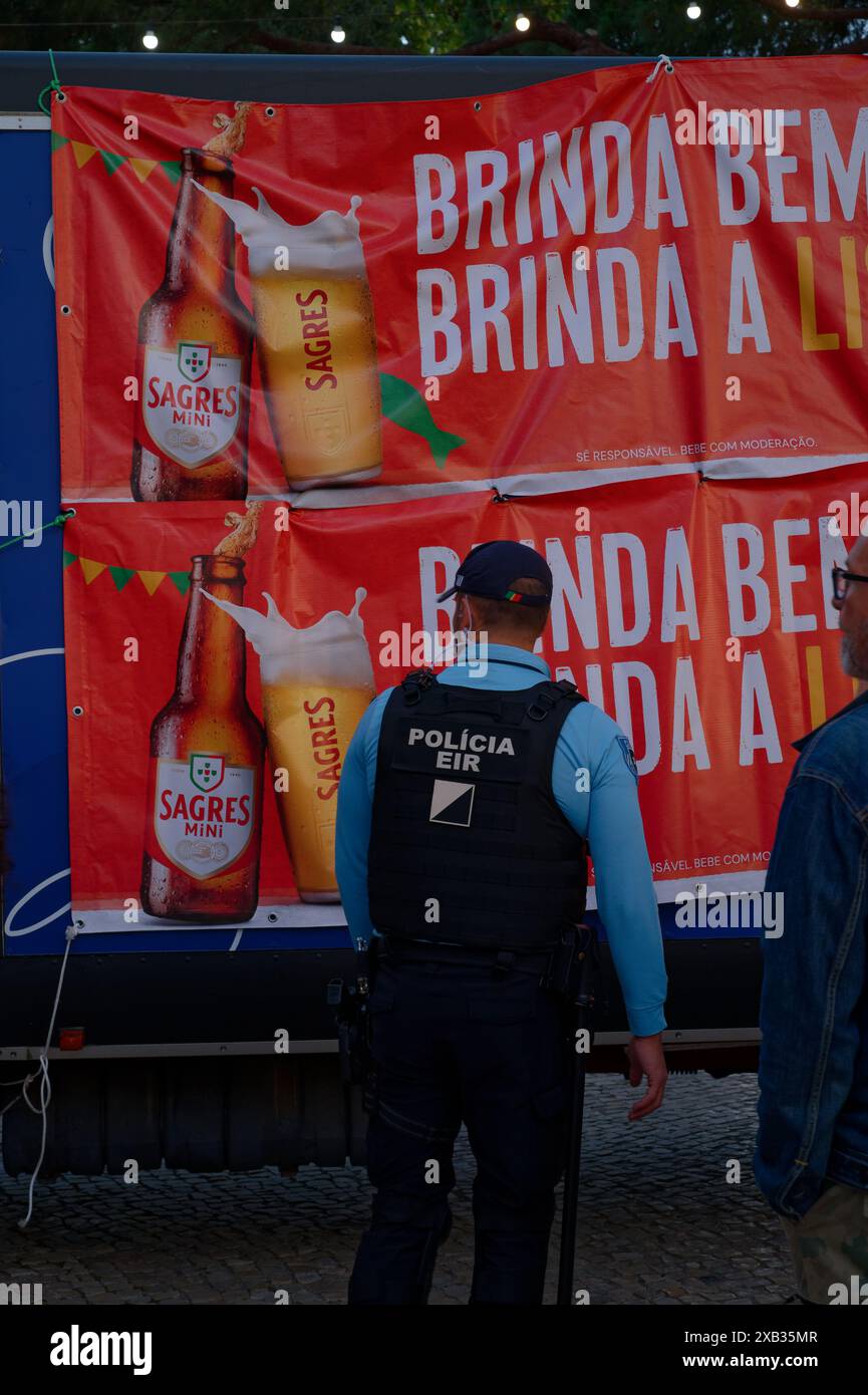 A police officer stands in front of a bright banner advertising Sagres ...