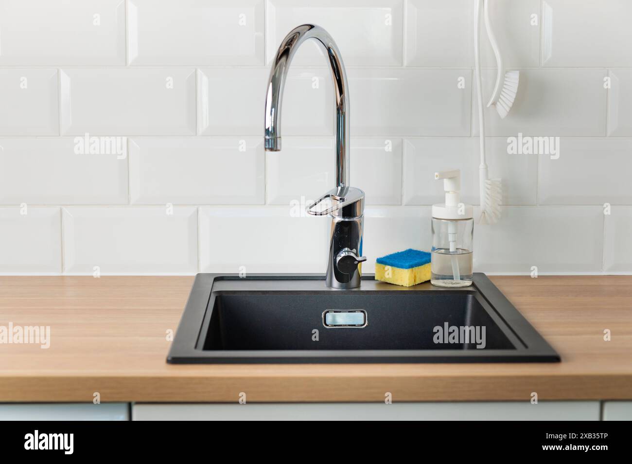 An empty black kitchen sink in a kitchen with a chrome faucet, wooden ...