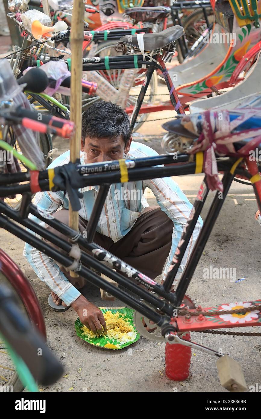 A rickshaw puller eats food distributed by a social worker on World ...