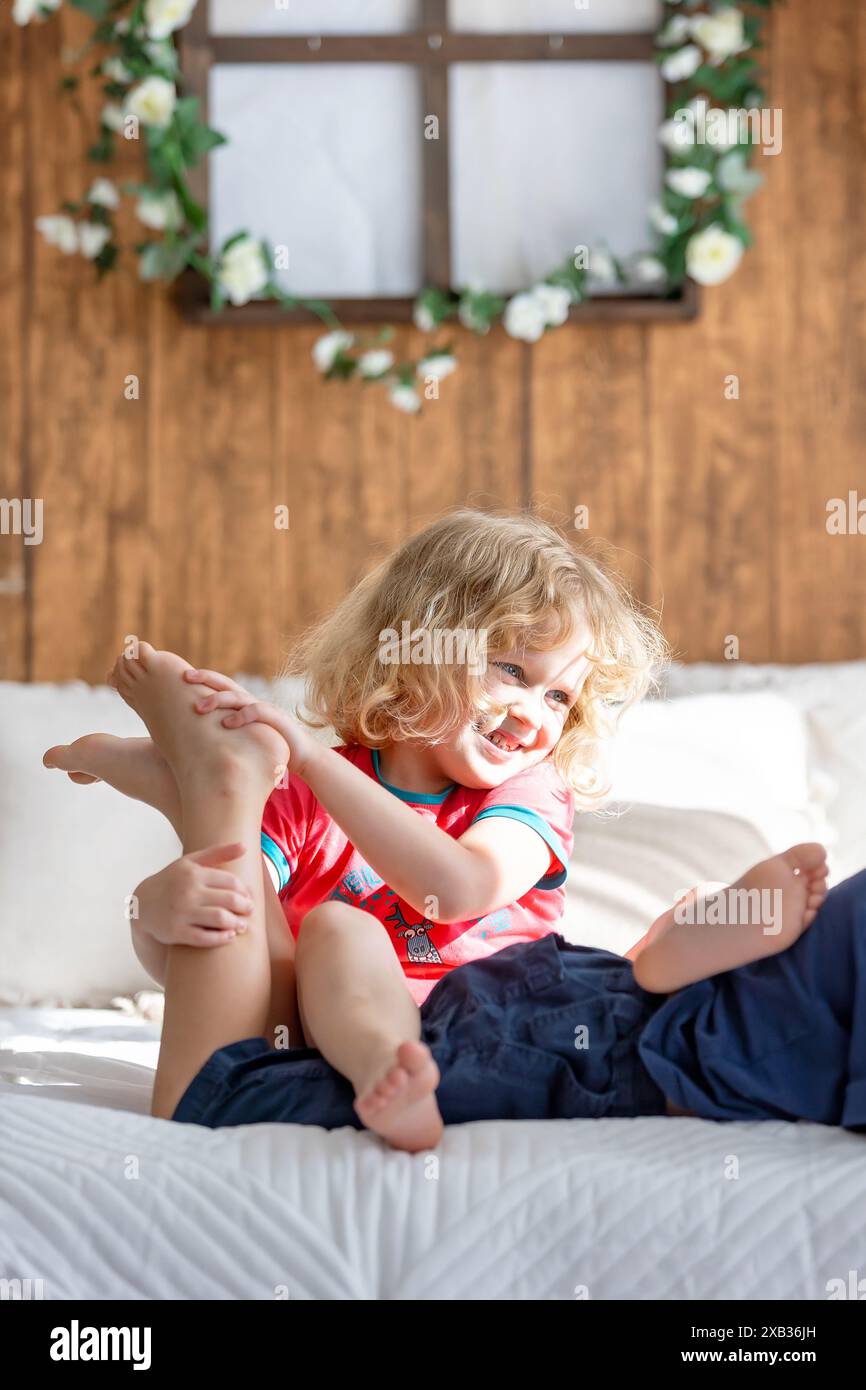 Cute sweet toddler children, tickling feet on the bed, laughing and ...