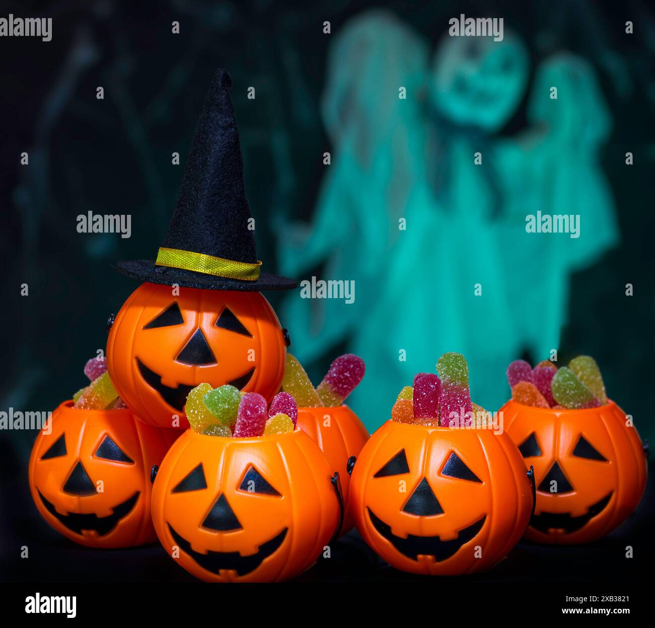 Plastic pumpkins filled with sweets, with a spooky ghost in the ...