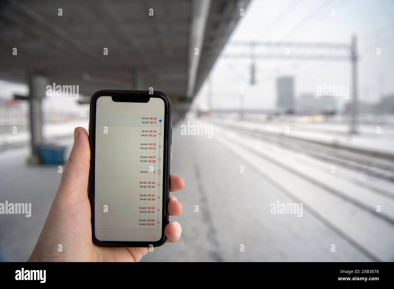 Hand of man holding smart phone at railway station Stock Photo - Alamy