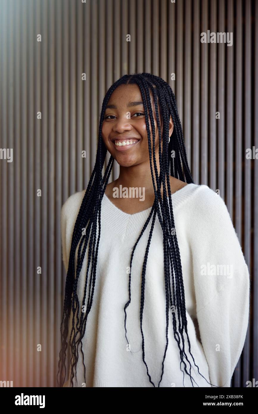 Happy young woman with braided hair standing against wall Stock Photo ...