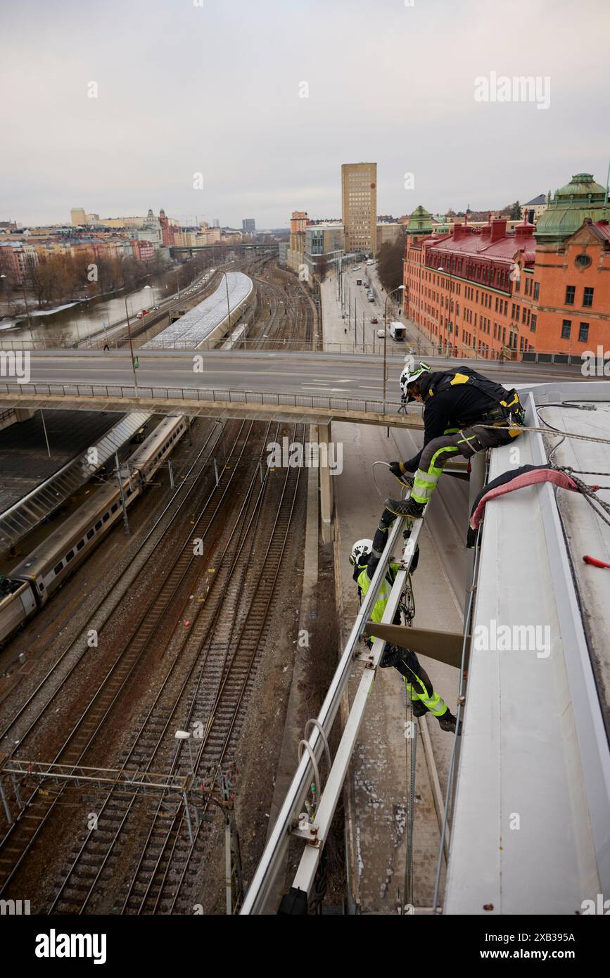 Rope access worker with coworker hanging from building in city Stock ...
