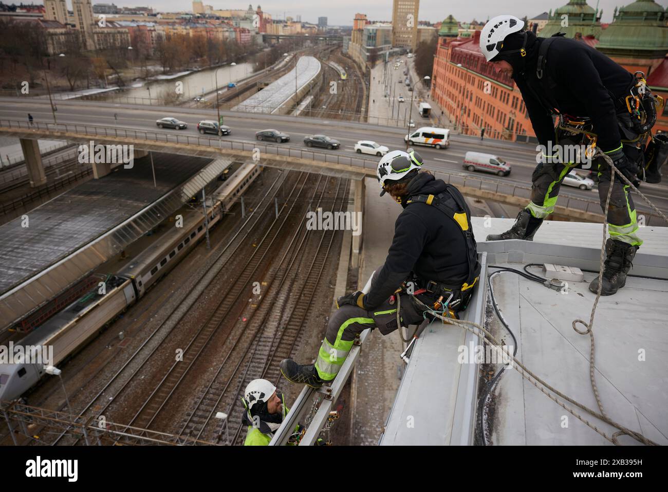 Rope access workers with colleague hanging from building in city Stock ...
