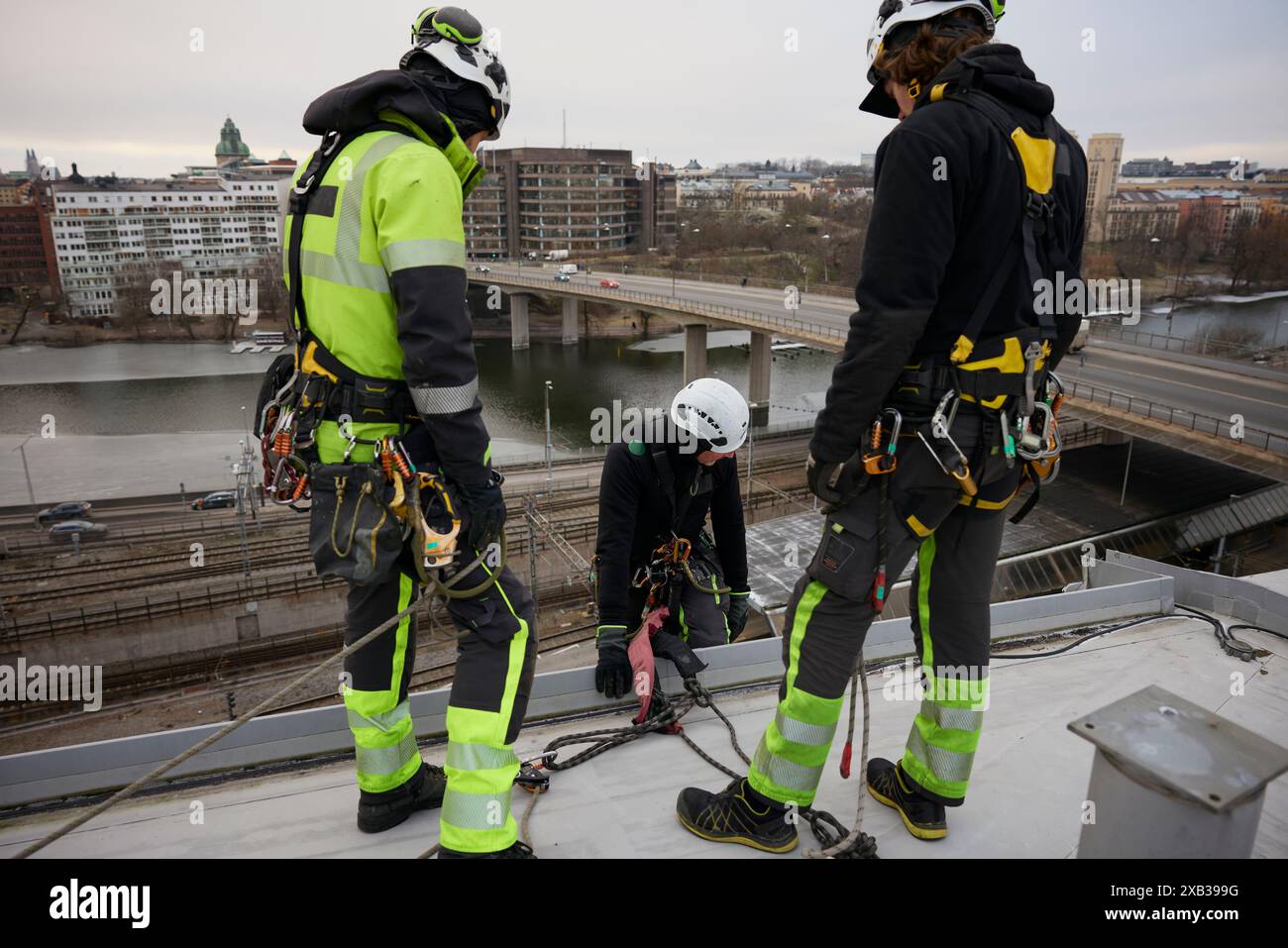 Male rope access workers looking at coworker on rooftop Stock Photo - Alamy