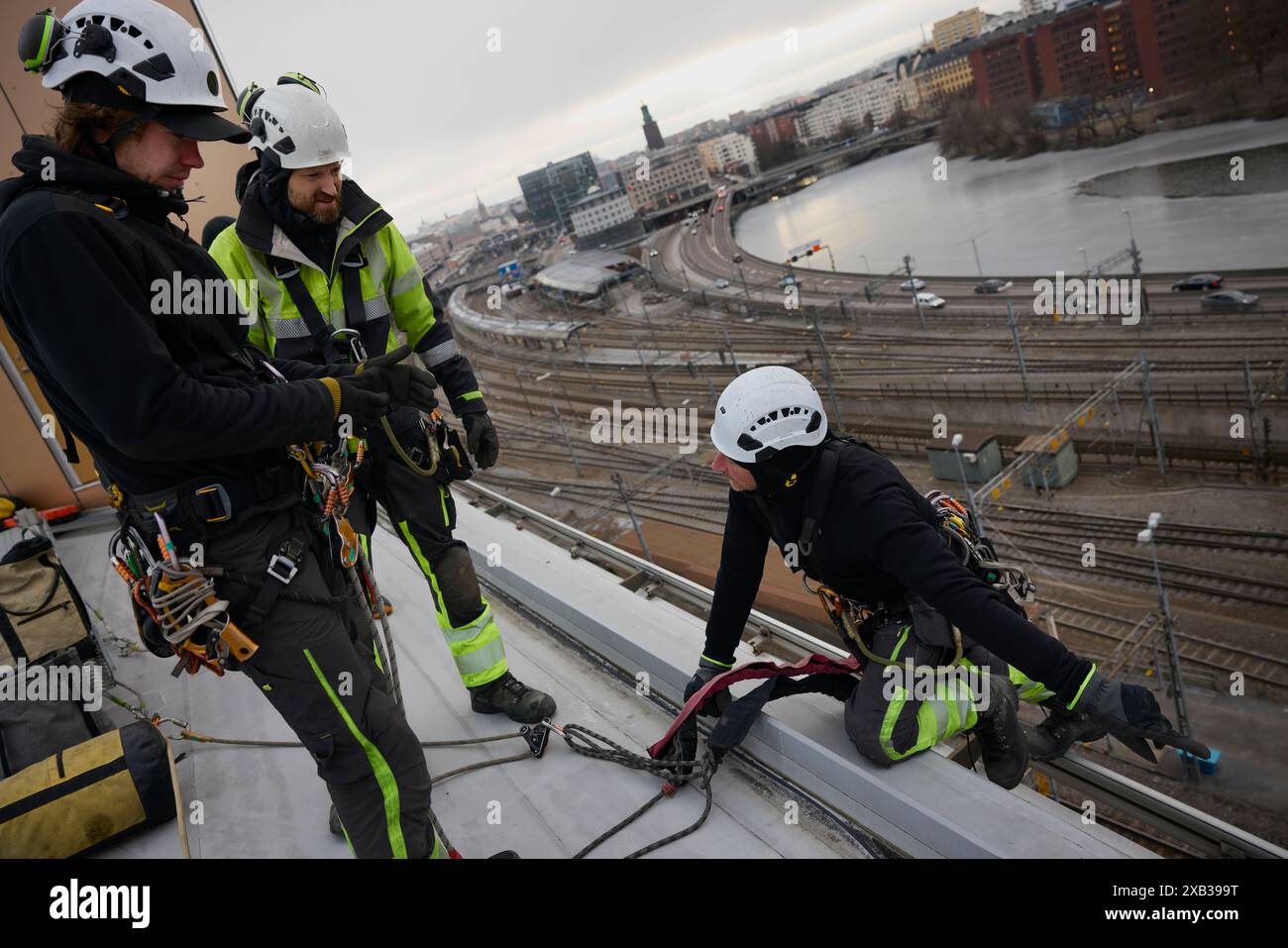 Male rope access workers assisting coworker on rooftop Stock Photo - Alamy