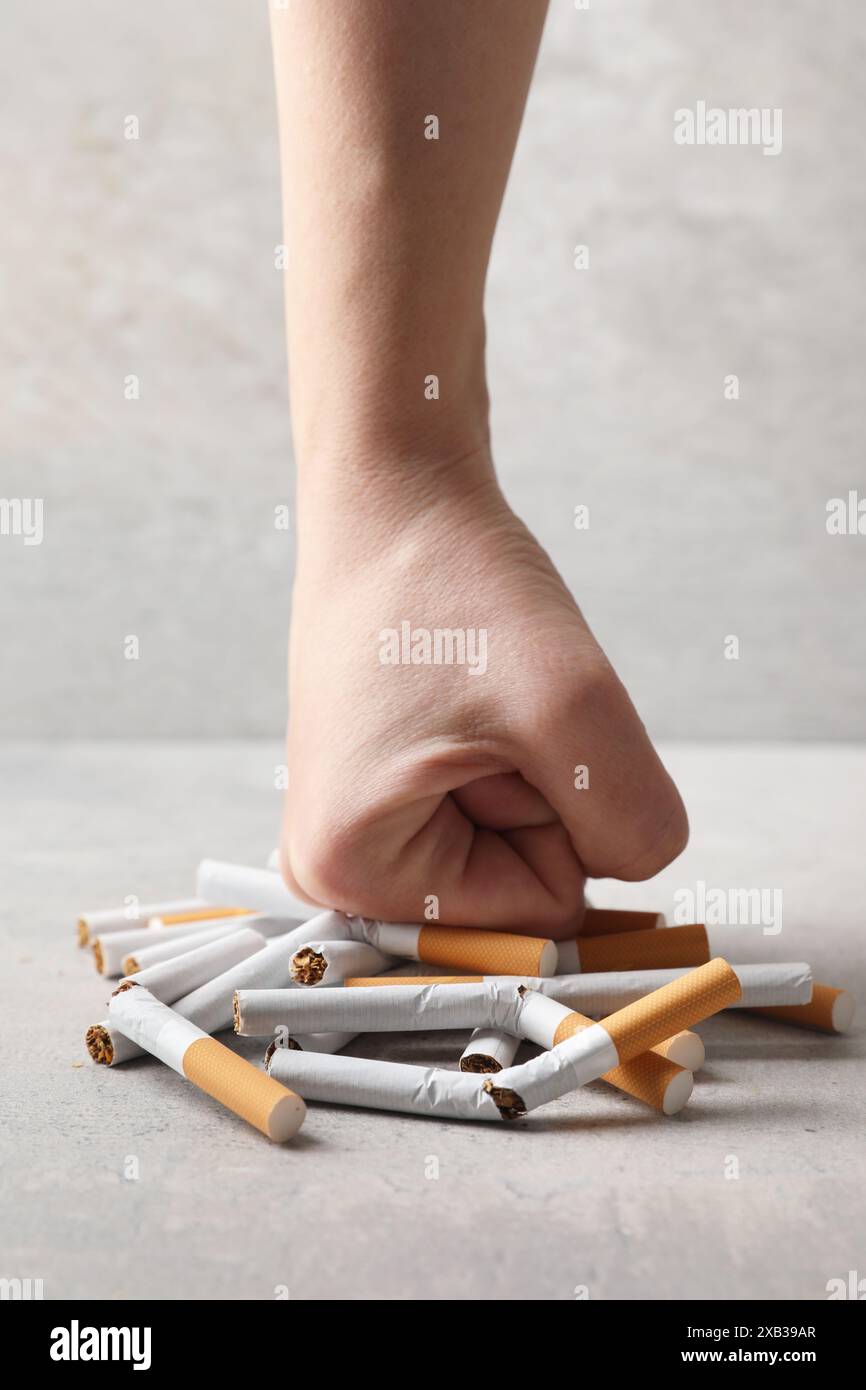 Stop smoking. Woman crushing cigarettes at grey table, closeup Stock ...