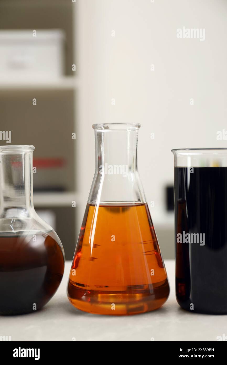 Flasks and beaker with different types of crude oil on light table ...