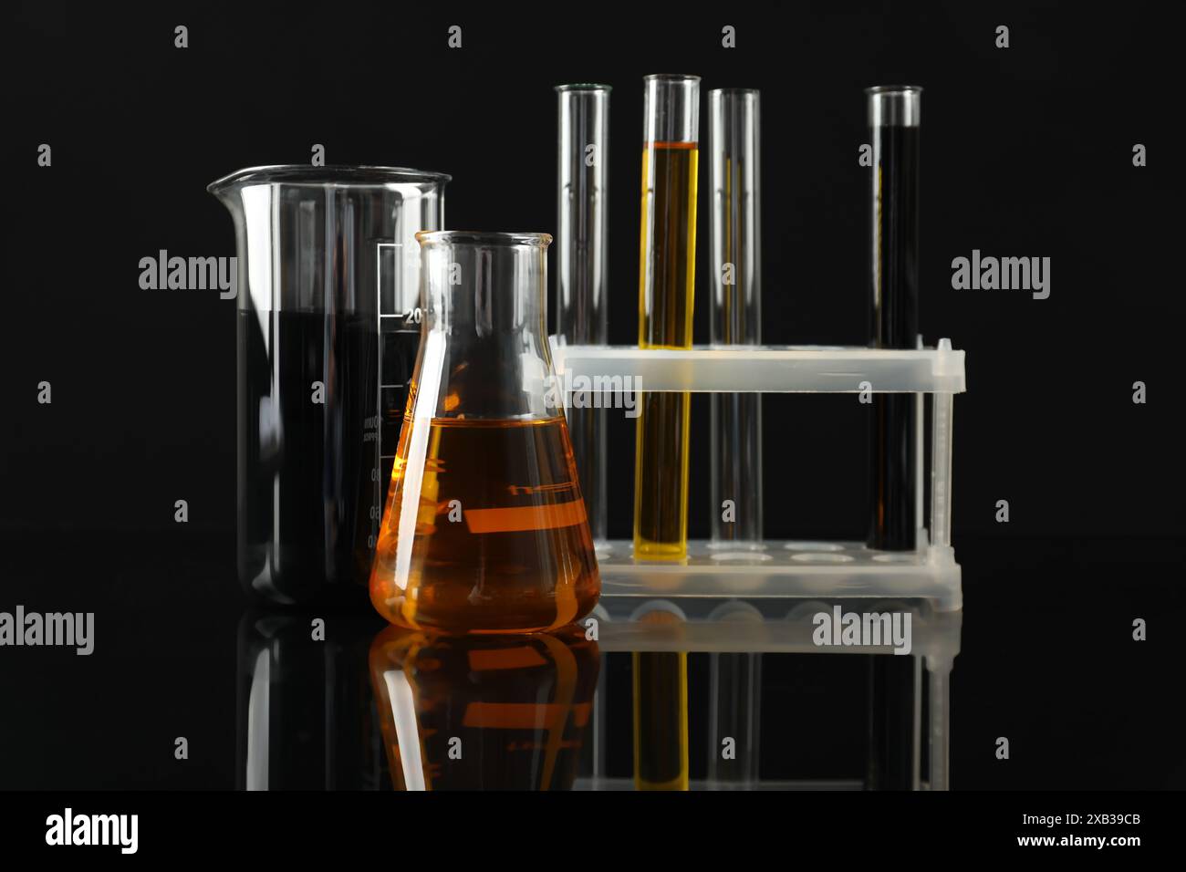 Laboratory glassware with different types of oil on black background ...