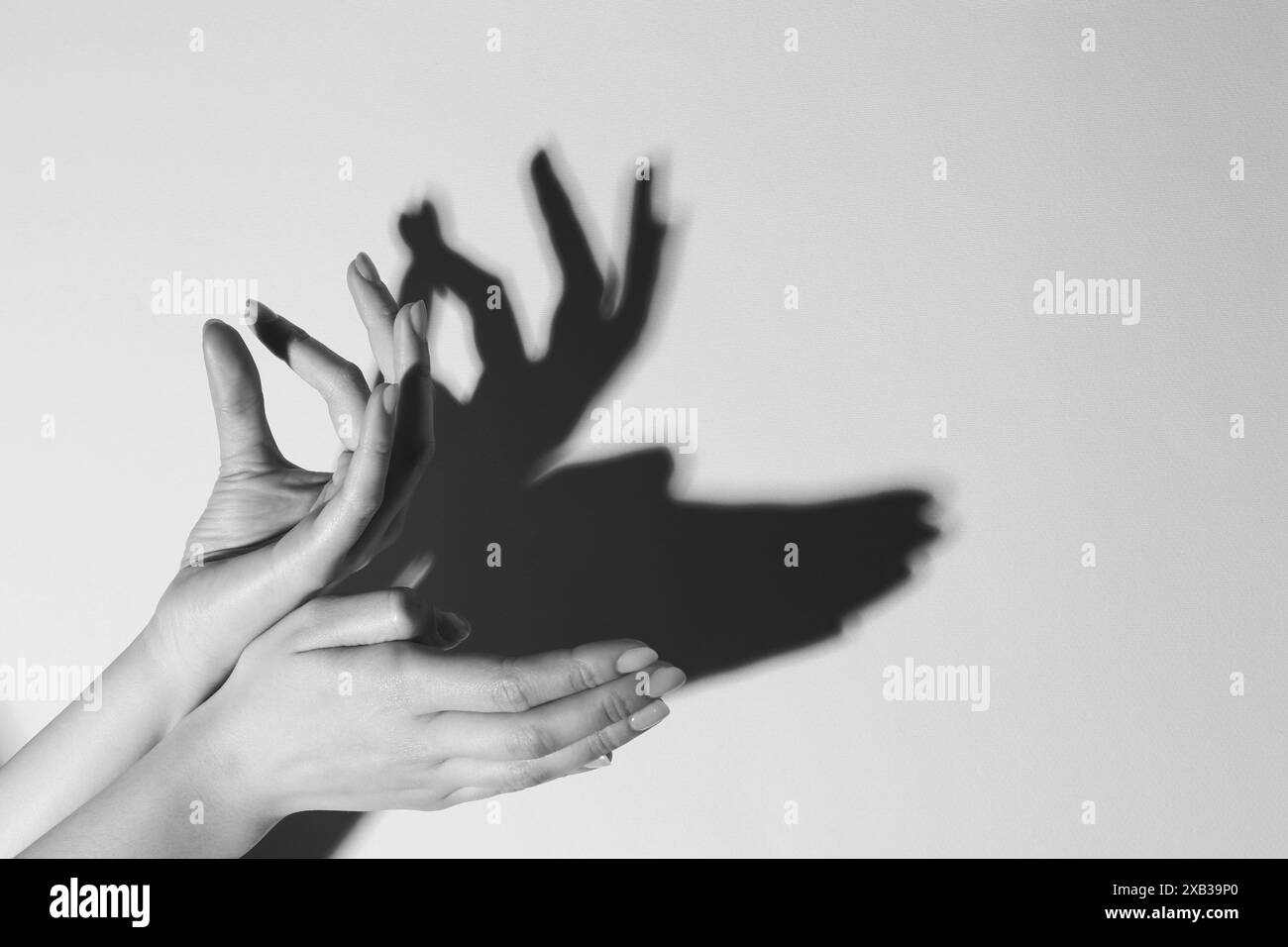 Shadow puppet. Woman making hand gesture like deer on light background, closeup with space for ...
