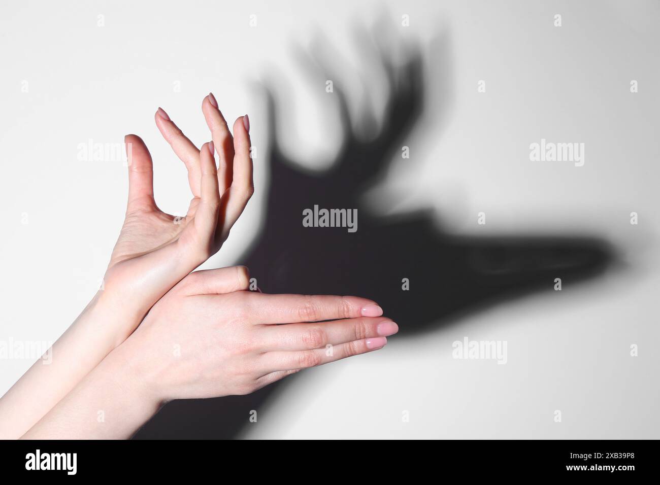 Shadow puppet. Woman making hand gesture like deer on light background ...
