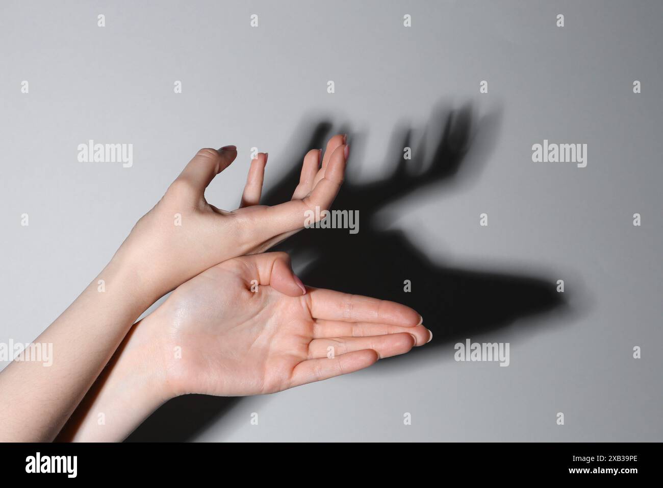 Shadow puppet. Woman making hand gesture like deer on grey background ...