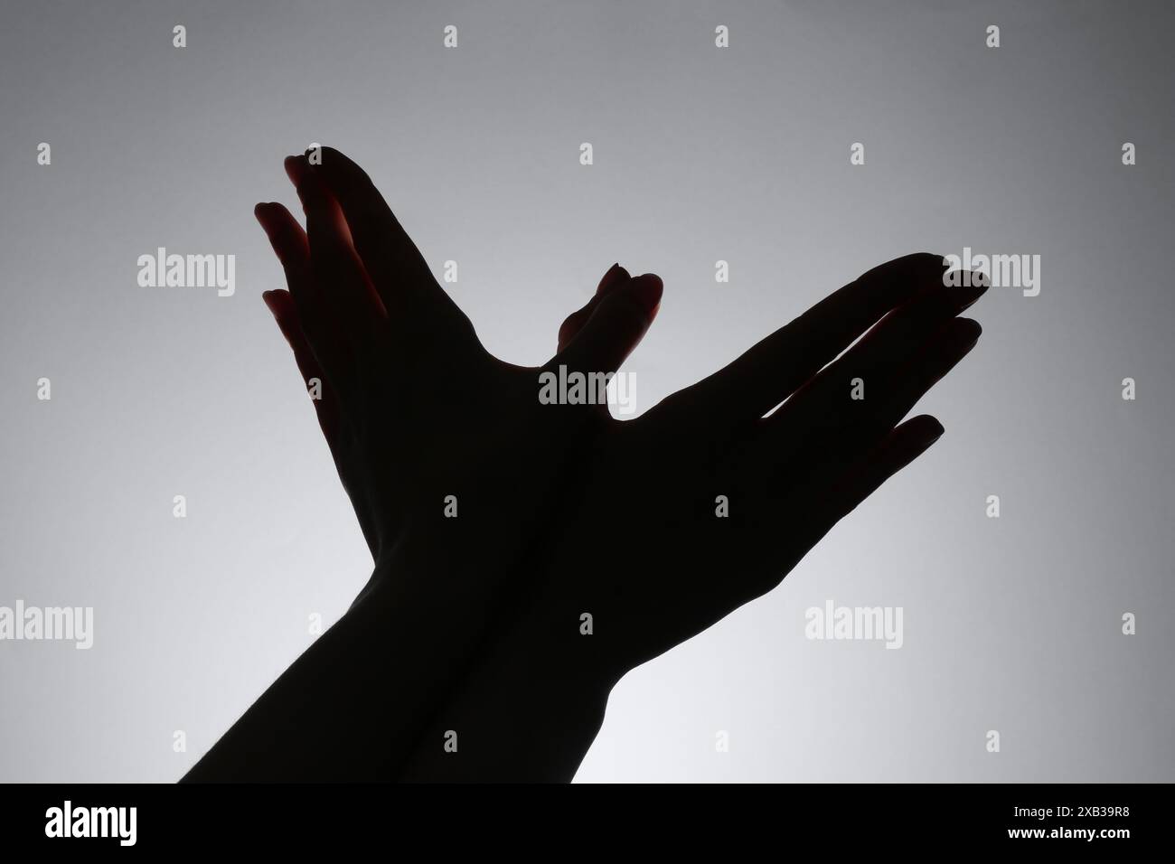 Shadow puppet. Woman making hand gesture like bird on grey background ...