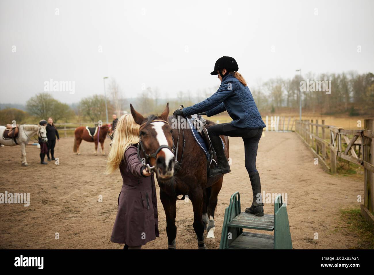 Girl sitting on horse with help of female instructor in ranch Stock ...