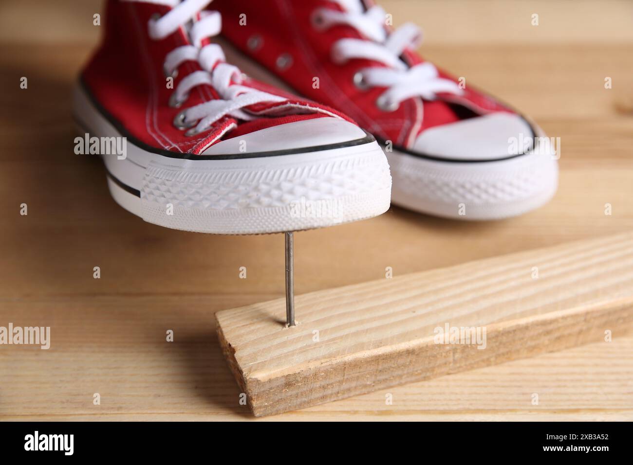 Metal nail in wooden plank and shoes on table, closeup Stock Photo - Alamy