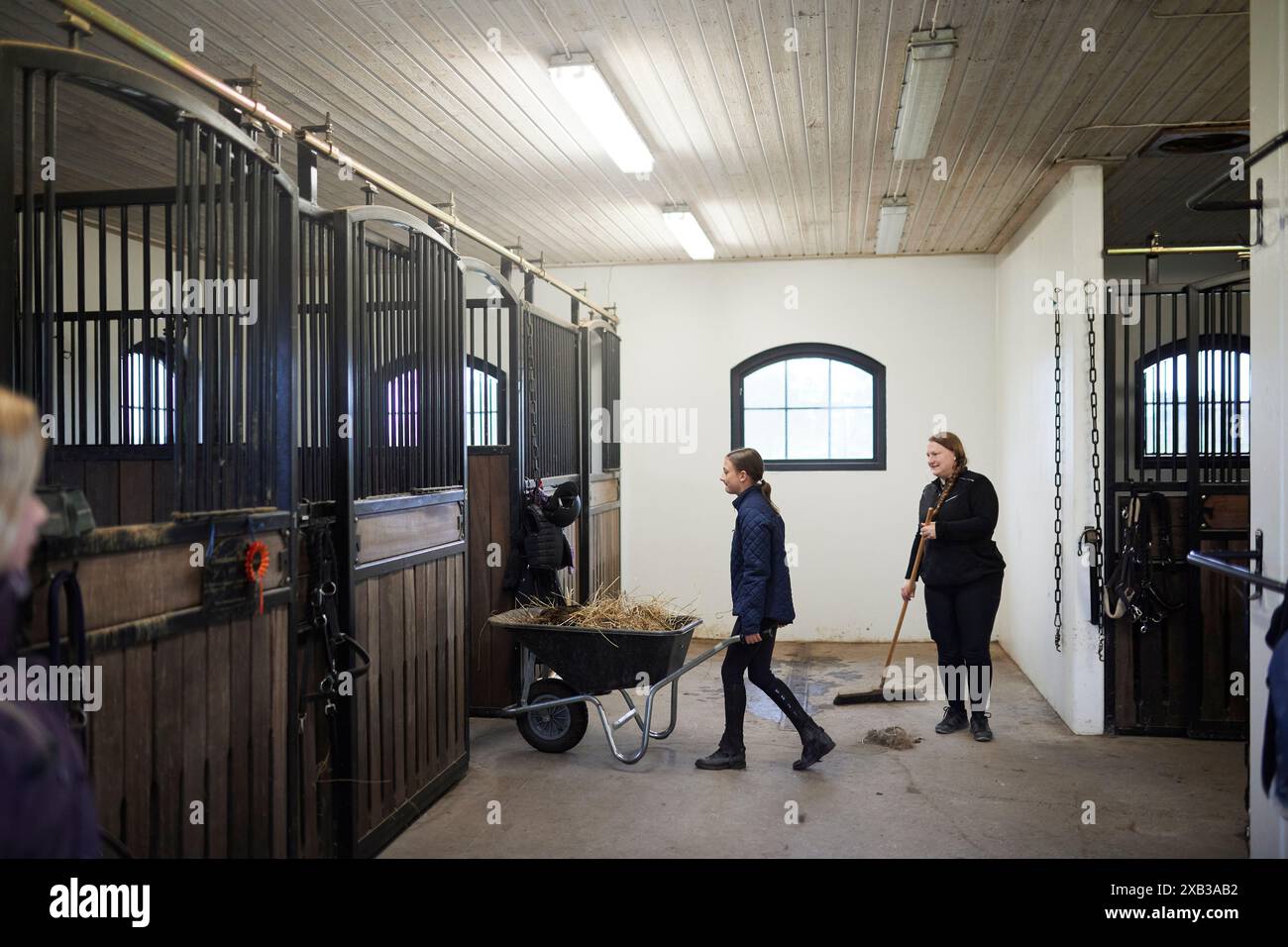 Girl and female farmer cleaning stable together Stock Photo - Alamy