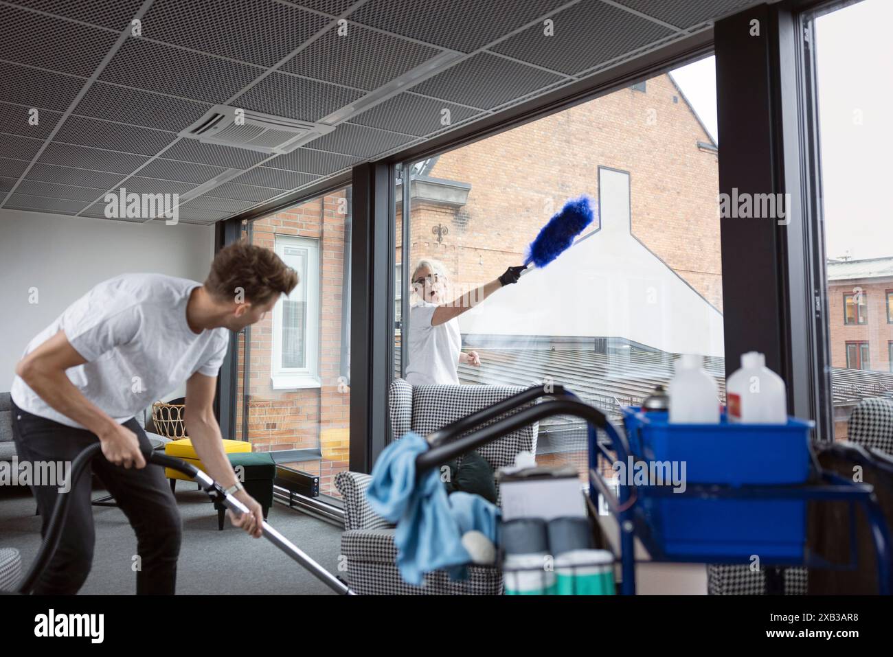 Male and female housekeeping staff cleaning lobby together Stock Photo ...