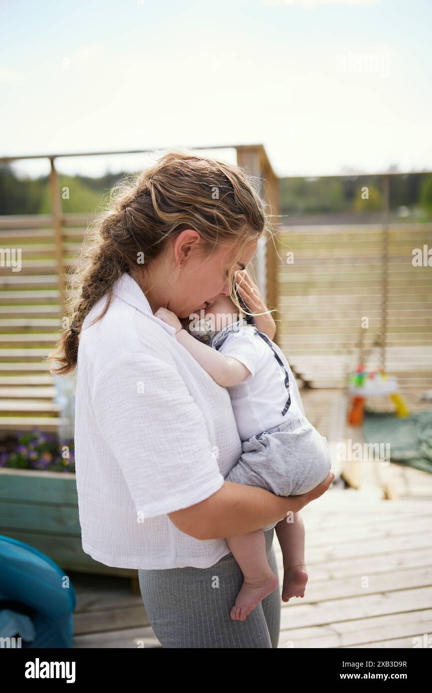 Side view of young mother carrying toddler son sleeping in back yard ... Side view of young mother carrying toddler son sleeping in back yard ...