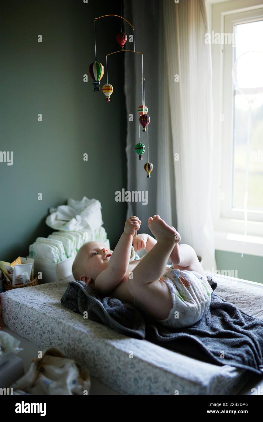 Baby lying under hanging mobile by window at home Stock Photo - Alamy