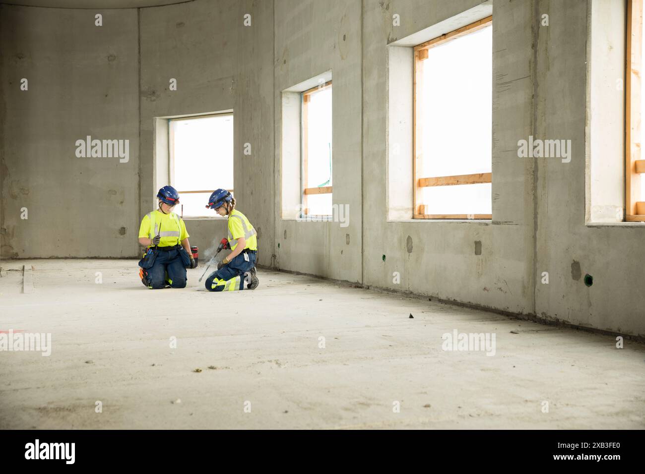 Female engineers kneeling and using equipment while working at ...