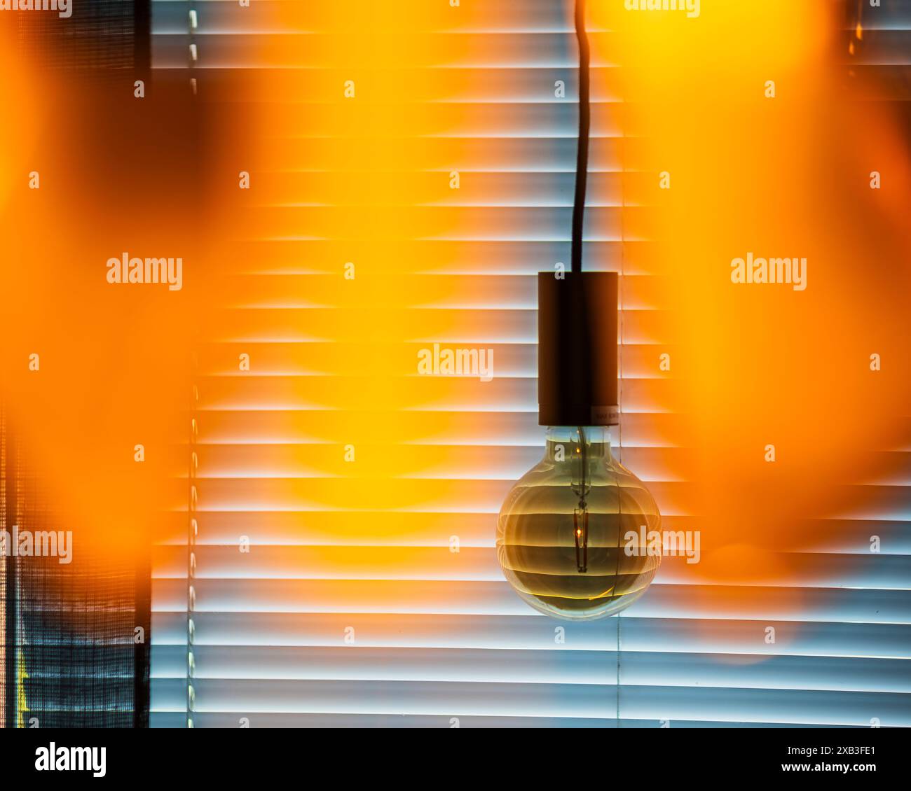 Light bulb hanging near window blinds Stock Photo - Alamy