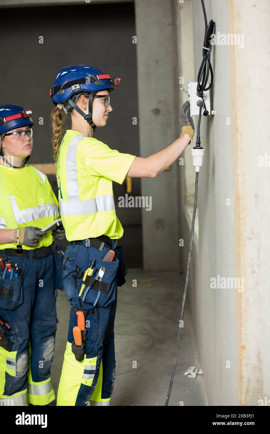 Female engineers working on electrical outlet at construction site ...