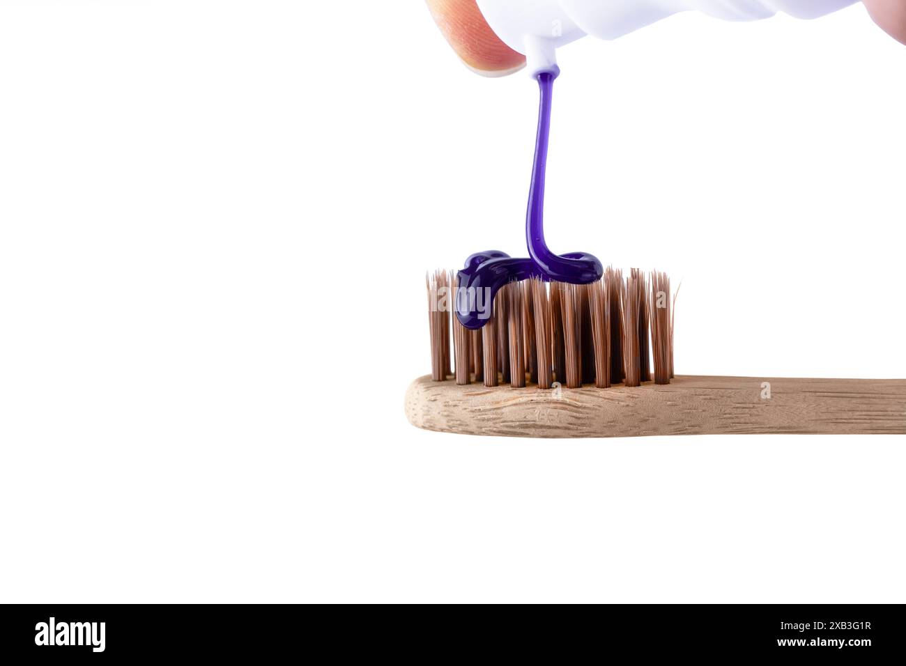 Pouring a whitening purple toothpaste on a toothbrush isolated on white ...